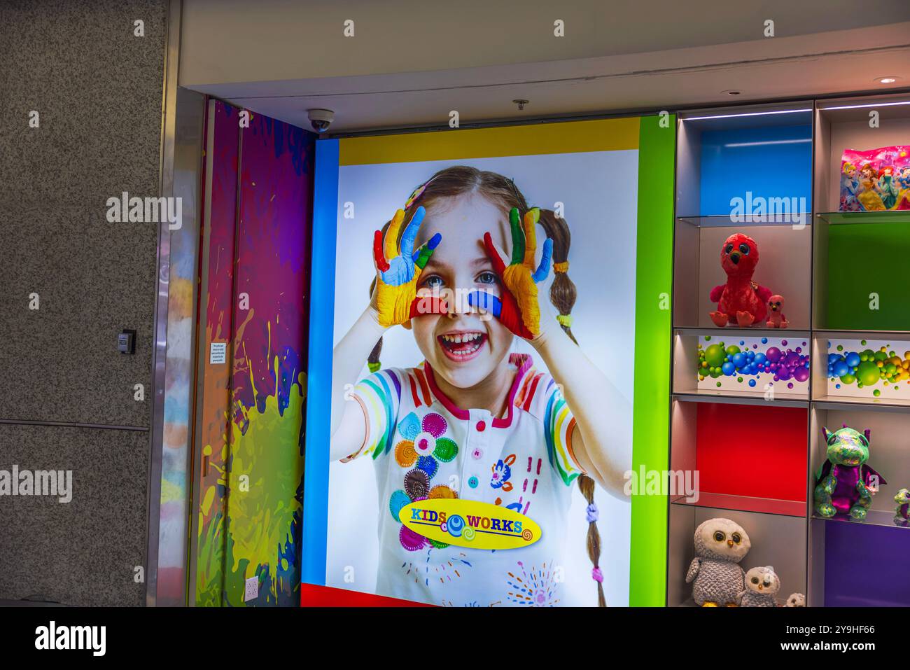 Colorful store display featuring child with painted hands and toys on ...