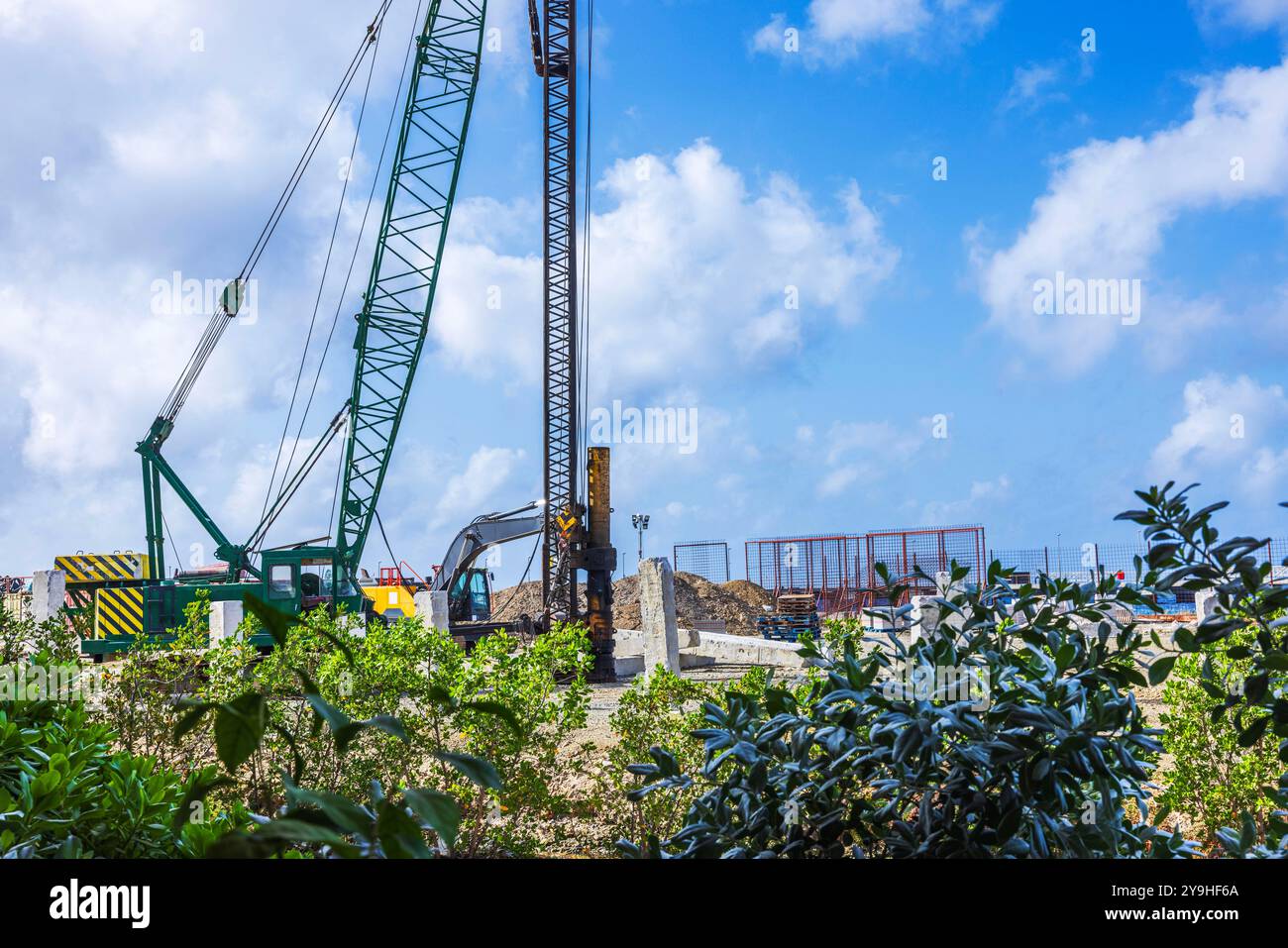 Construction site with cranes and machinery under clear sky in tropical ...
