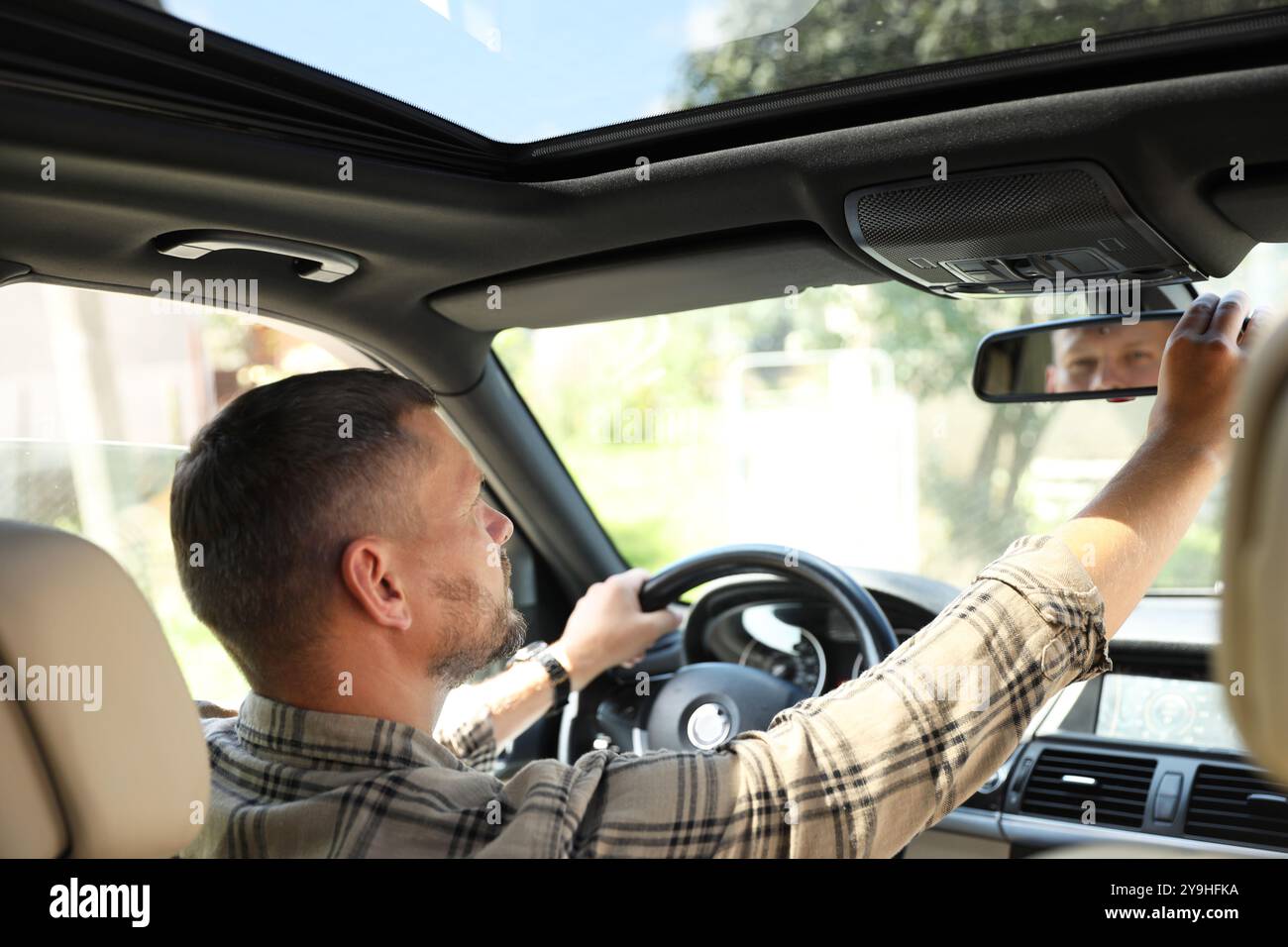 Man adjusting rear view mirror while driving car Stock Photo - Alamy
