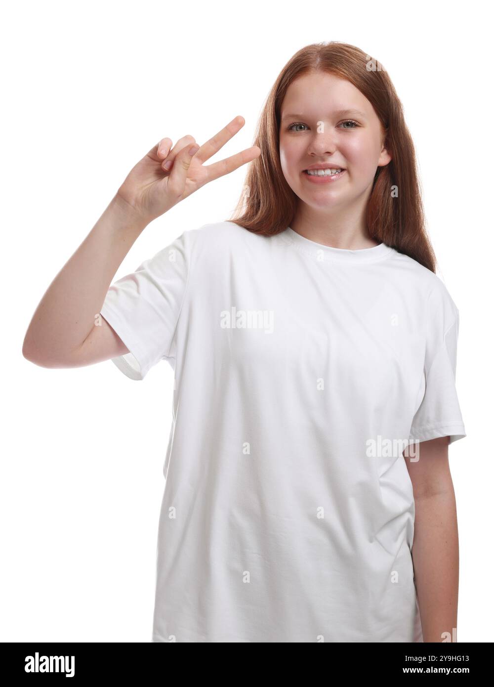 Teenage girl showing v-sign on white background Stock Photo - Alamy