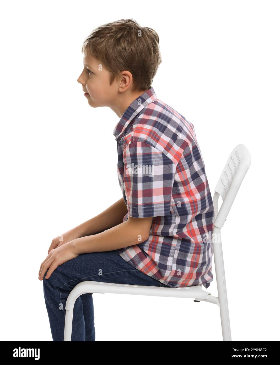 Boy with incorrect posture sitting on chair against white background ...