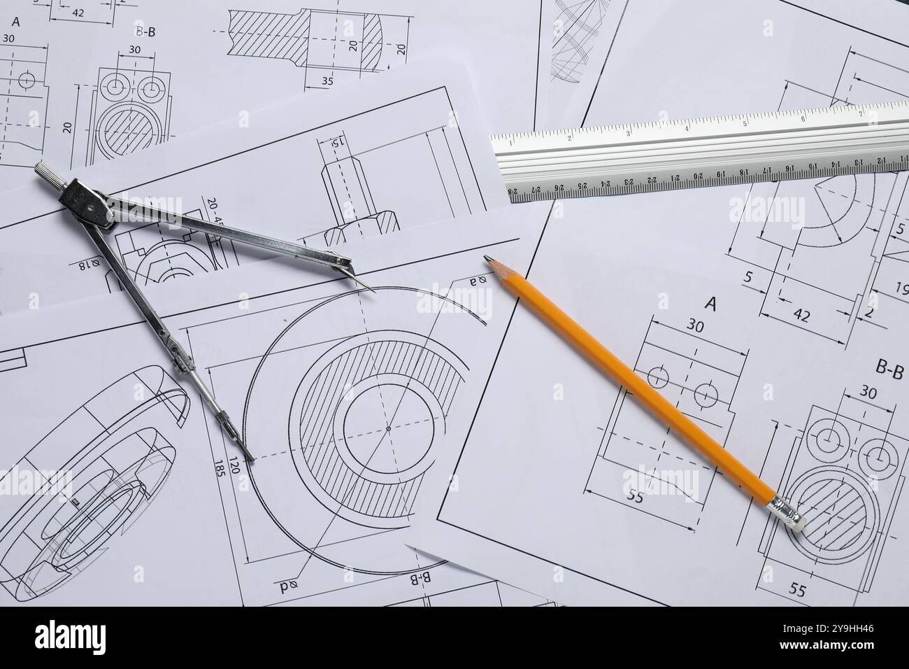 Different engineering drawings, pencil, ruler and divider on table ...