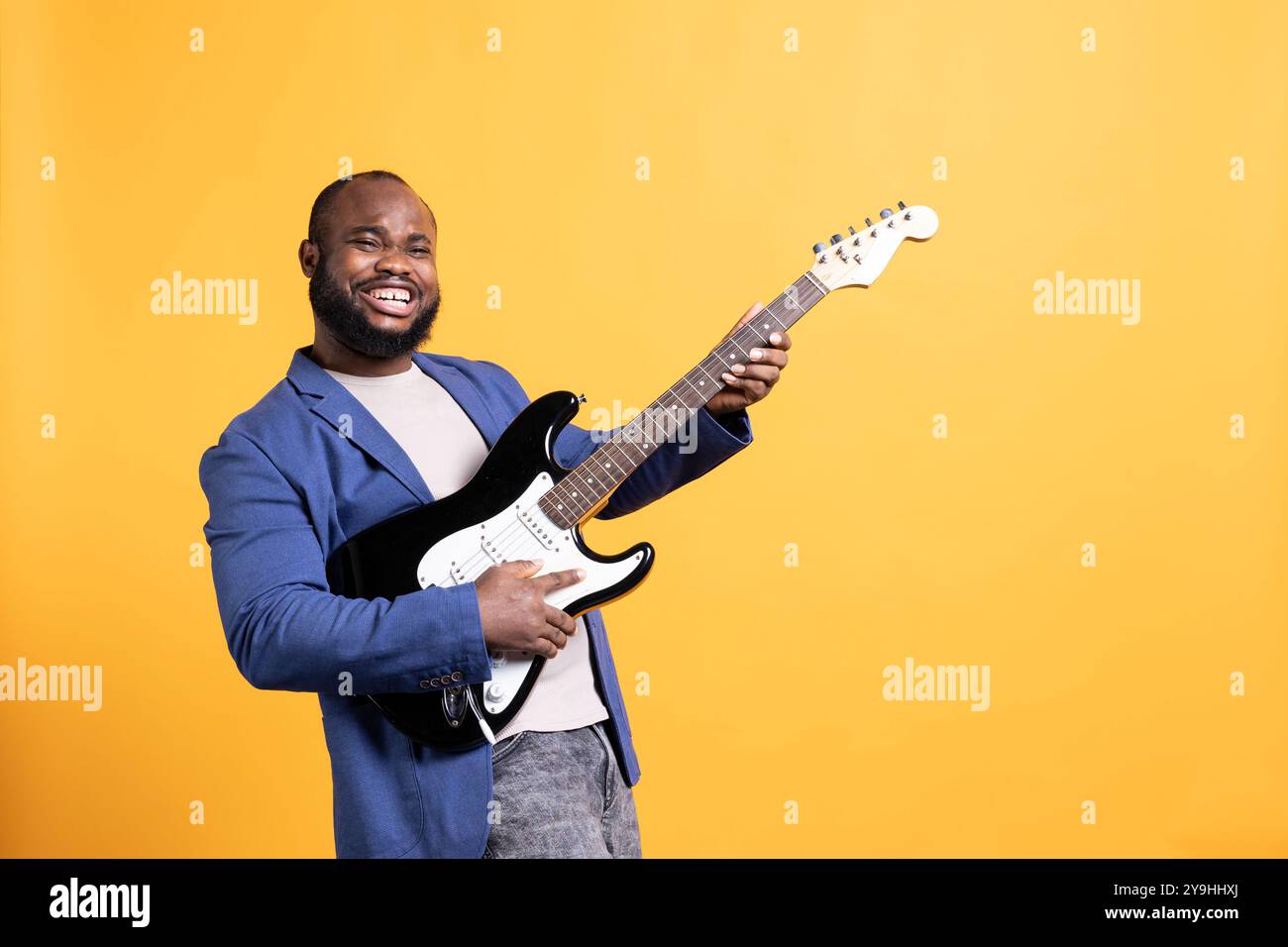 Portrait of ecstatic man holding guitar, excited to perform rock tunes ...