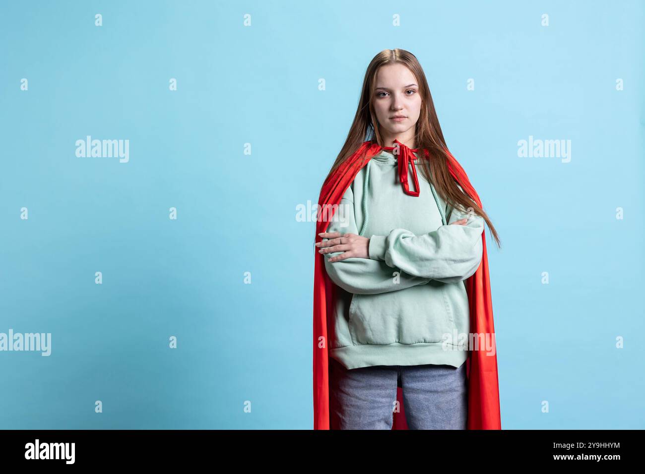 Teenager portraying superhero, wearing red cape, isolated over studio ...