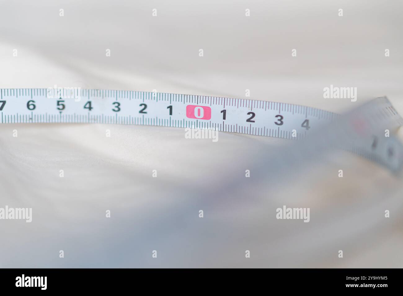 A close-up of a measuring tape lying on a soft surface, showing the ...