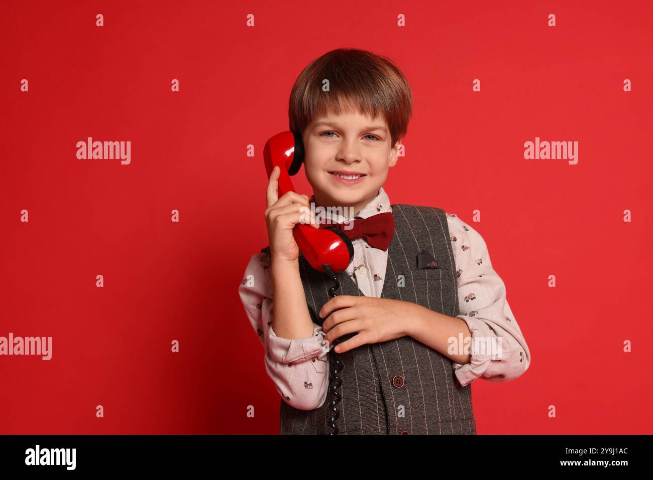 Cute little boy with handset of telephone on red background, space for ...