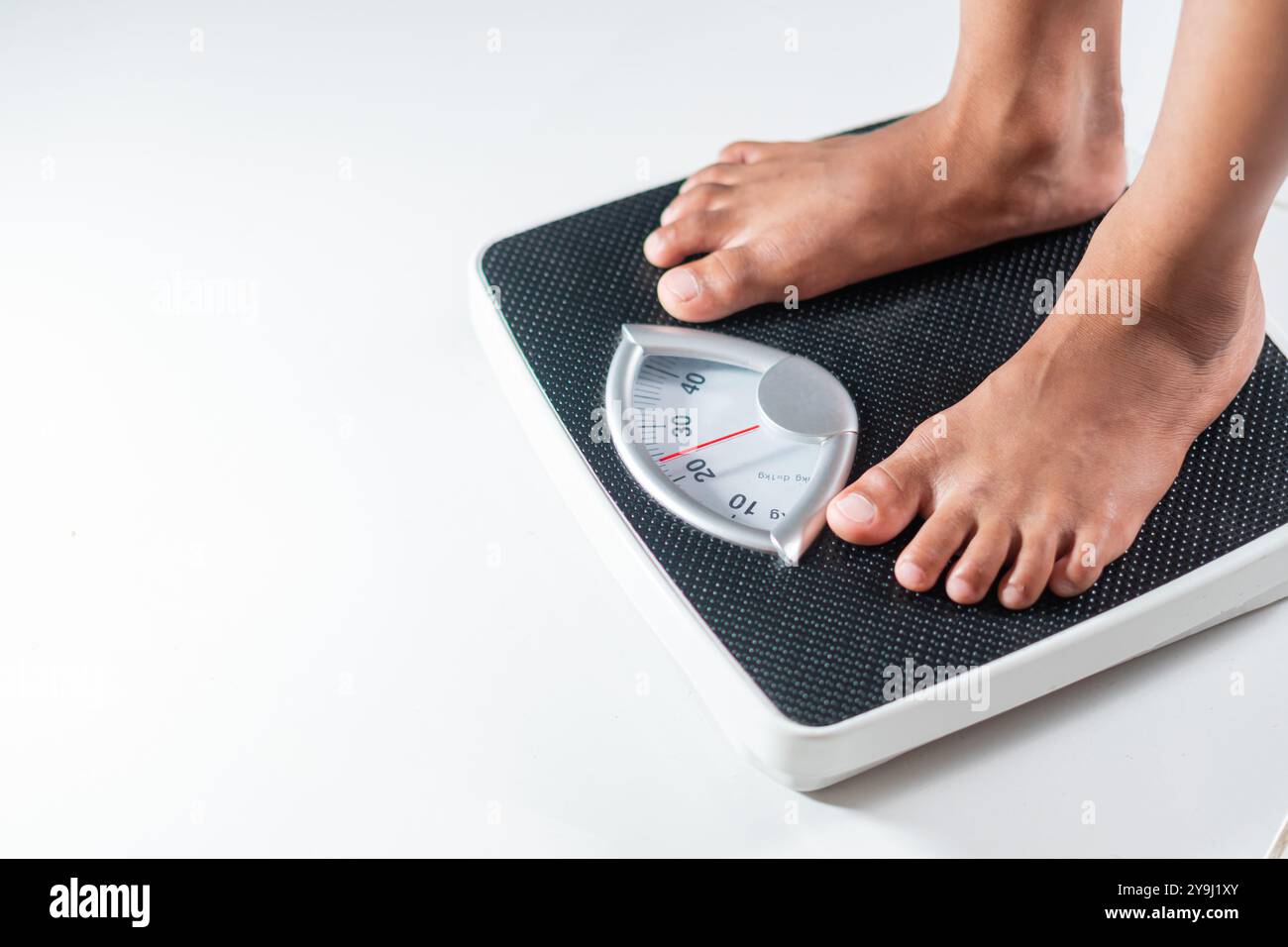 A person standing on a mechanical bathroom scale, showing a close-up of ...