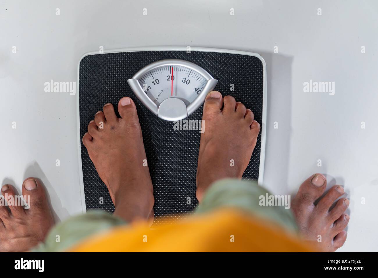 A person standing on a weighing scale, showing their feet and the scale ...