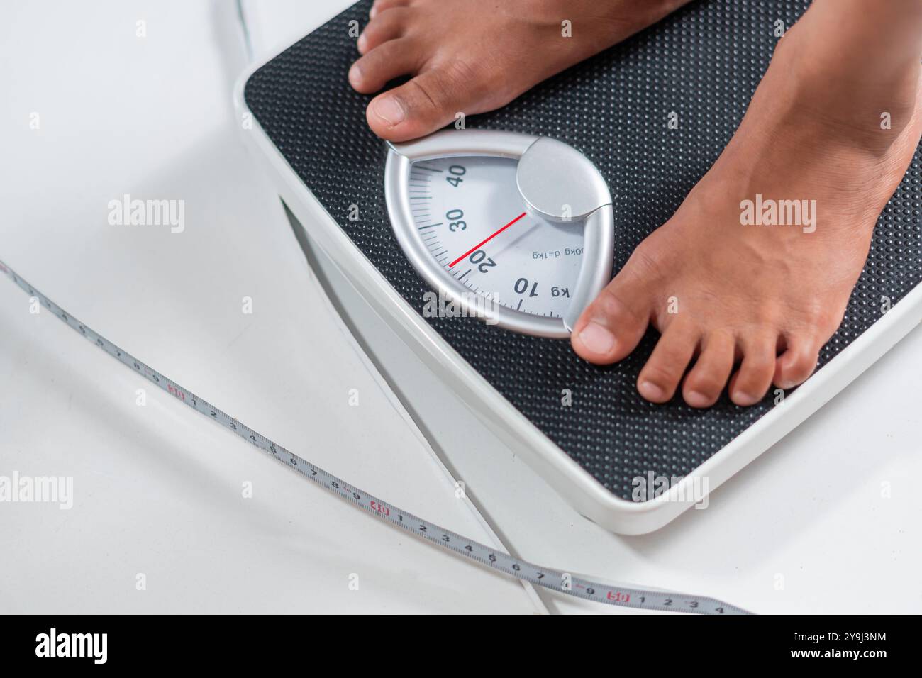 A close-up of a person standing on a mechanical weighing scale. The ...