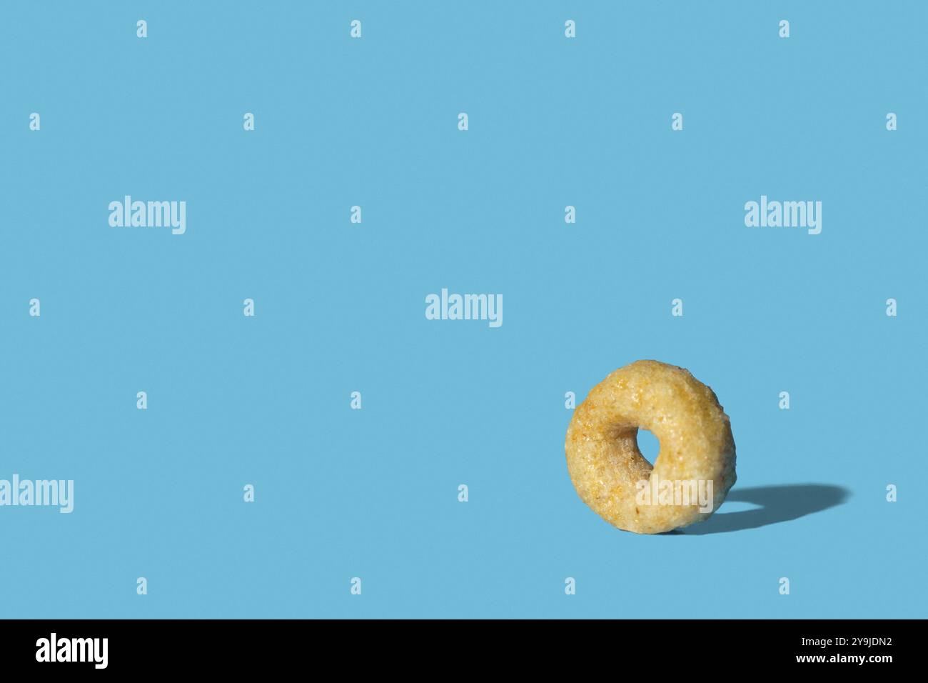 One Cheerios cereal loop with a hard shadow on a blue background with ...