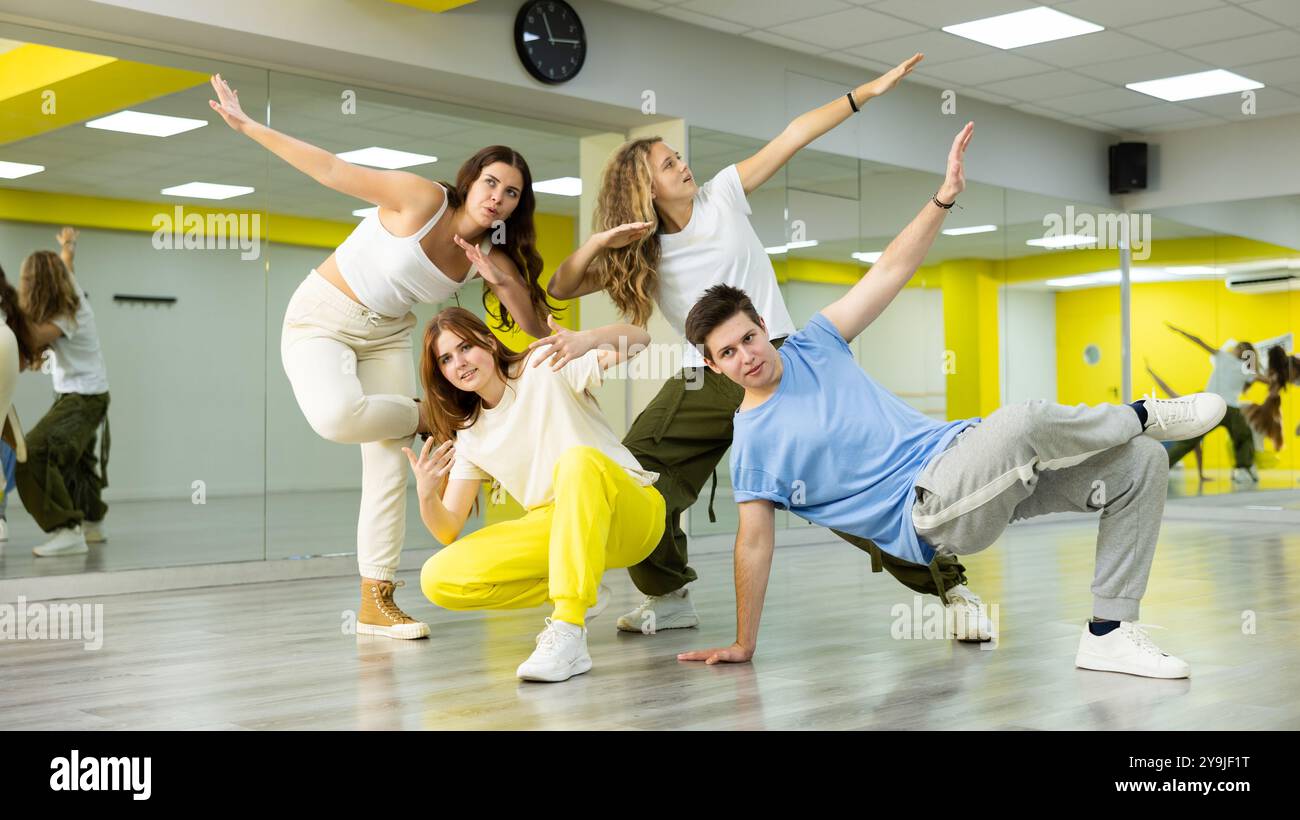 Teenage girls and a boy performing breakdance poses in dance hall Stock ...