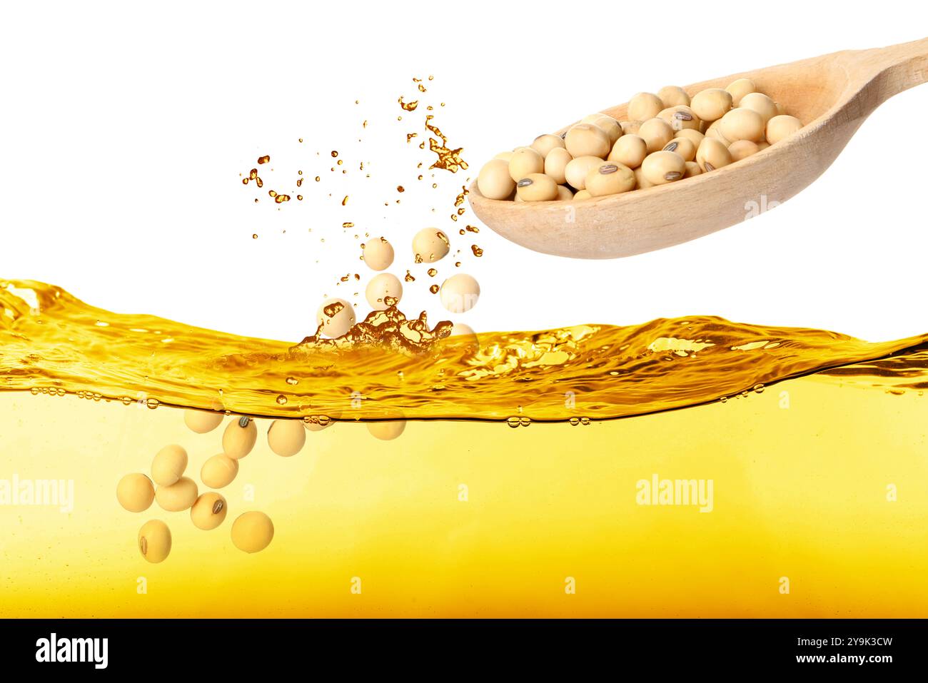 Soy beans falling from wooden spoon into vegetable oil on white ...