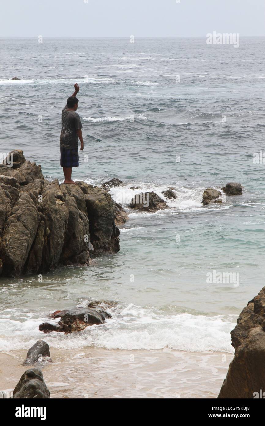 Zipolite, Oaxaca, México; 10 25 2015; A man standing on a rock at the ...