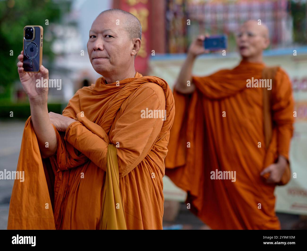 Two Thai Buddhist monks in Phuket Town, Thailand, watching a procession during the local ...
