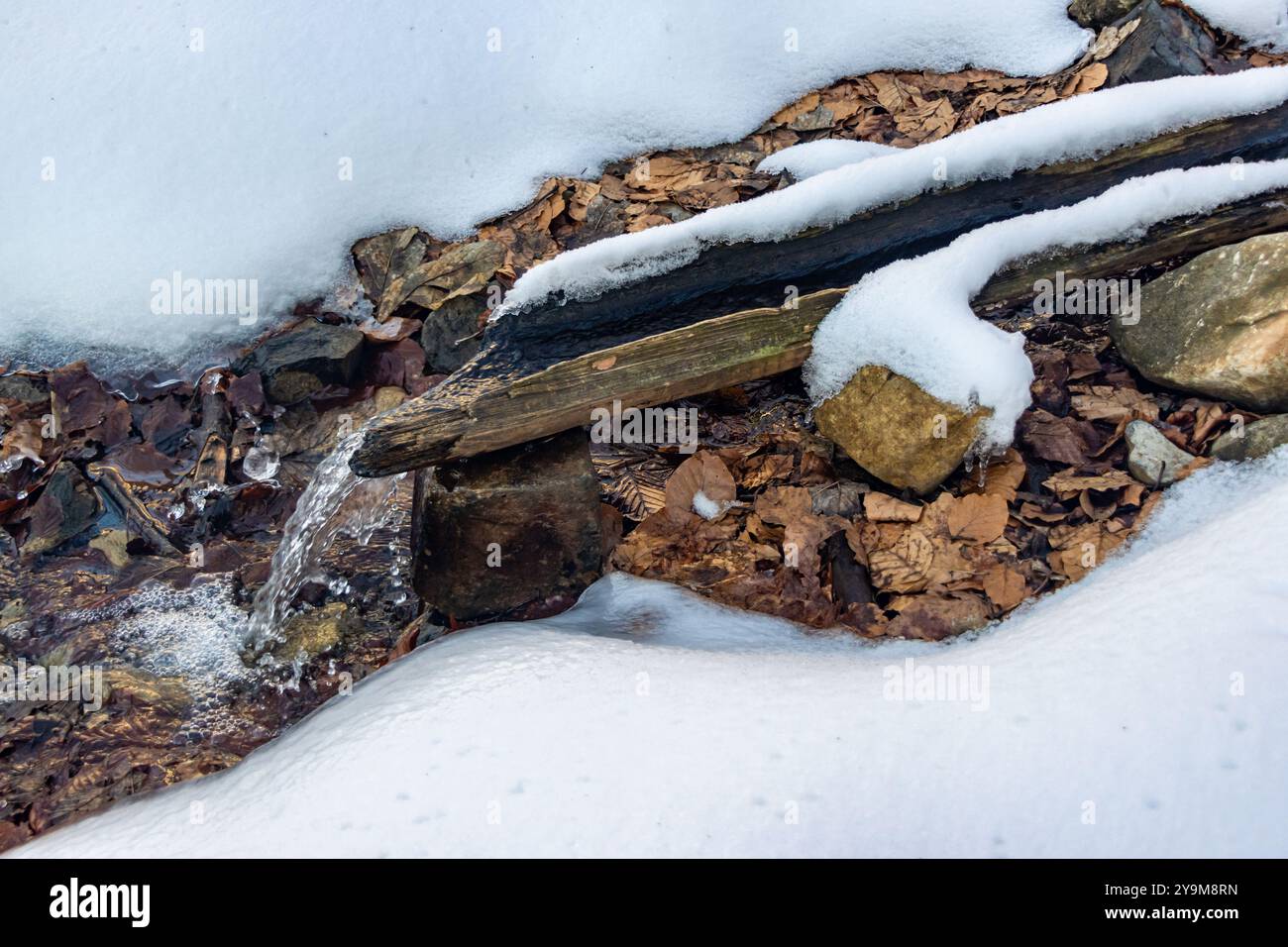 Water flows through a wooden trough in a snowy landscape Stock Photo ...