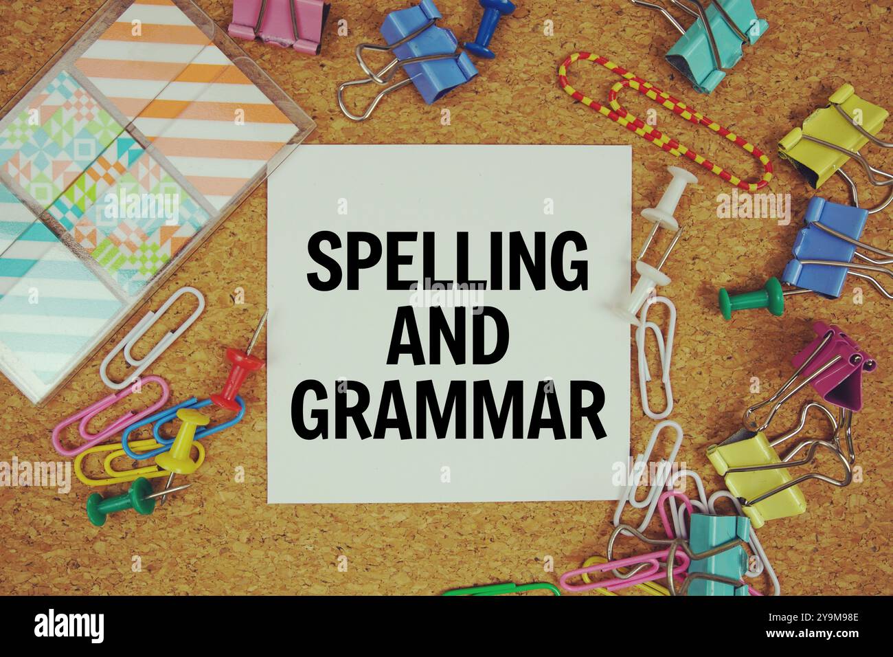 Spelling and Grammar text on paper card with stationery on cork board ...