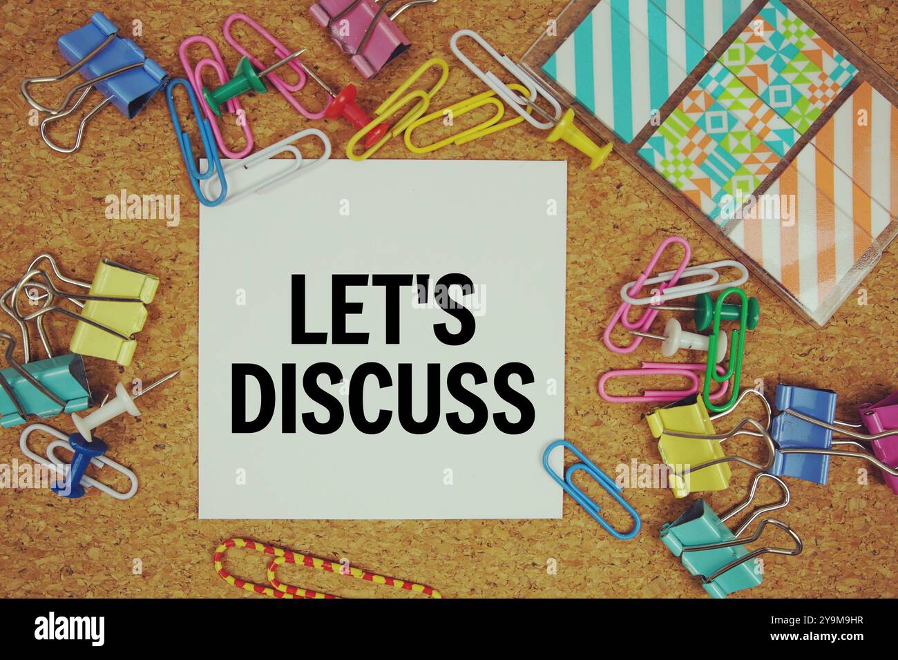Let's Discuss text on paper card with stationery on cork board ...
