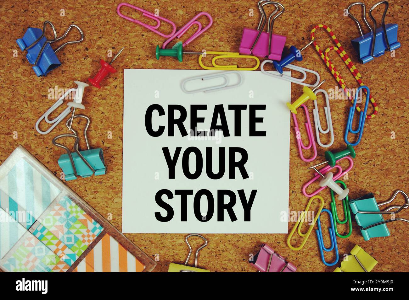 Create Your Story text on paper card with stationery on cork board ...
