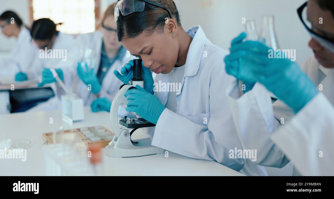 Science, student and study with microscope in classroom for sample ...
