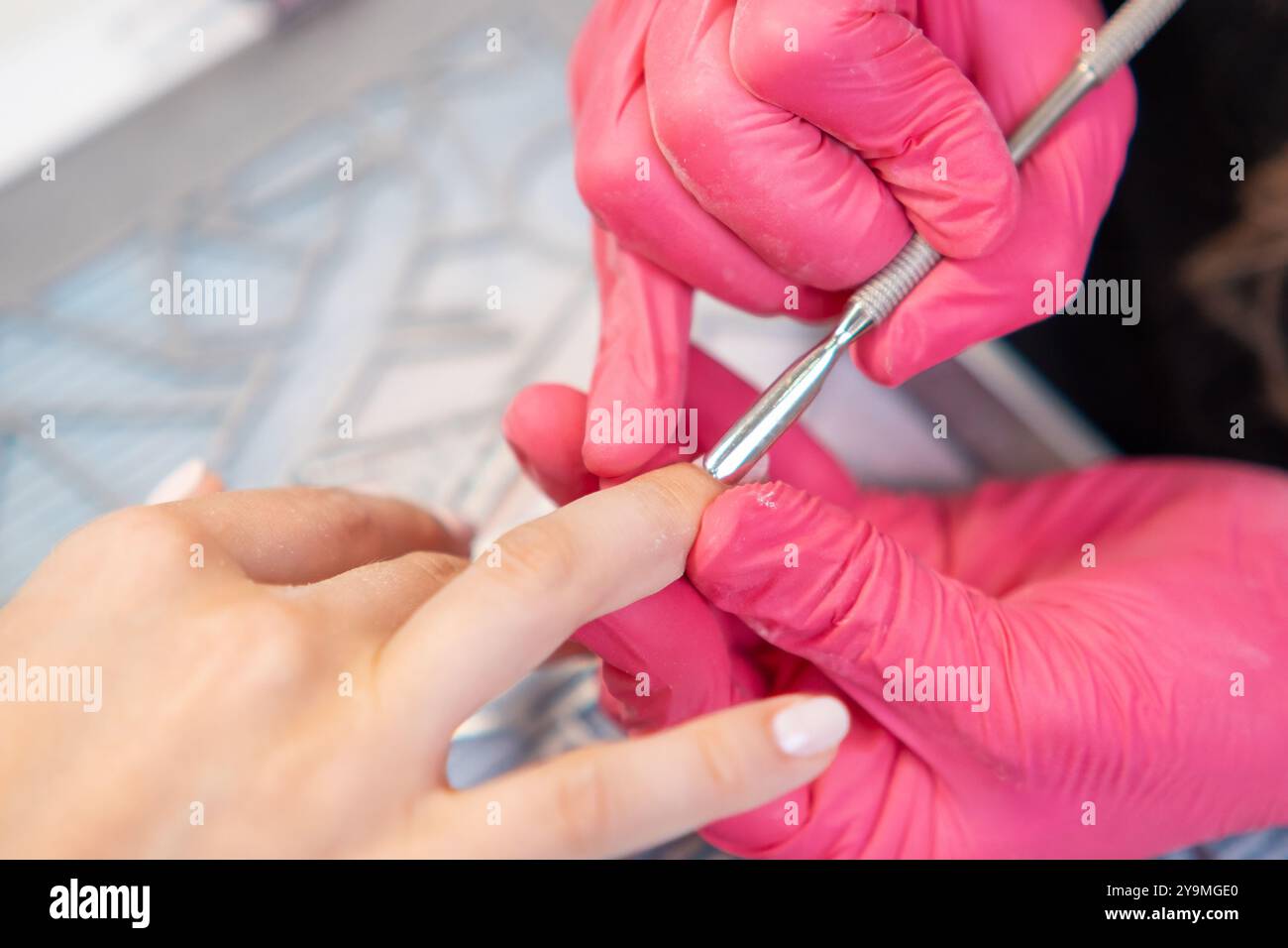 Nail master works on a clients fingers, gently removing cuticles in a ...
