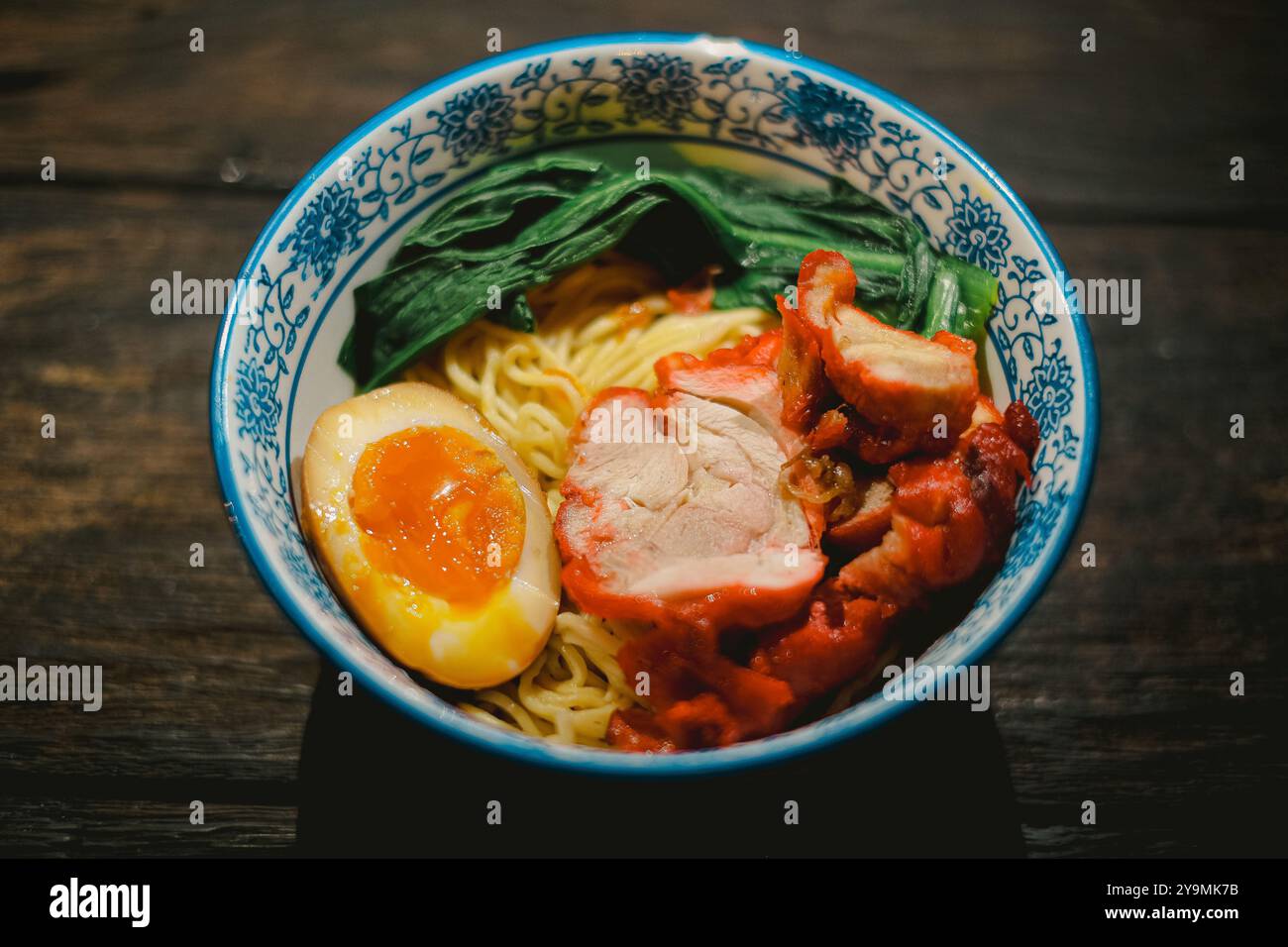 Chinese fried noodles in a bowl with Char Siu, hard-boiled egg, and a ...