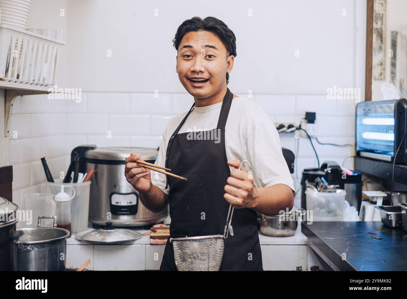 A Southeast Asian chef with an apron is drying up the noodles in the ...