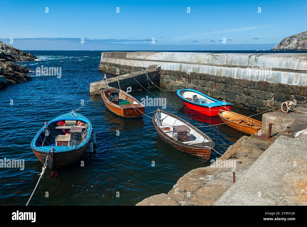 A harbor with several small boats docked. The boats are all different ...