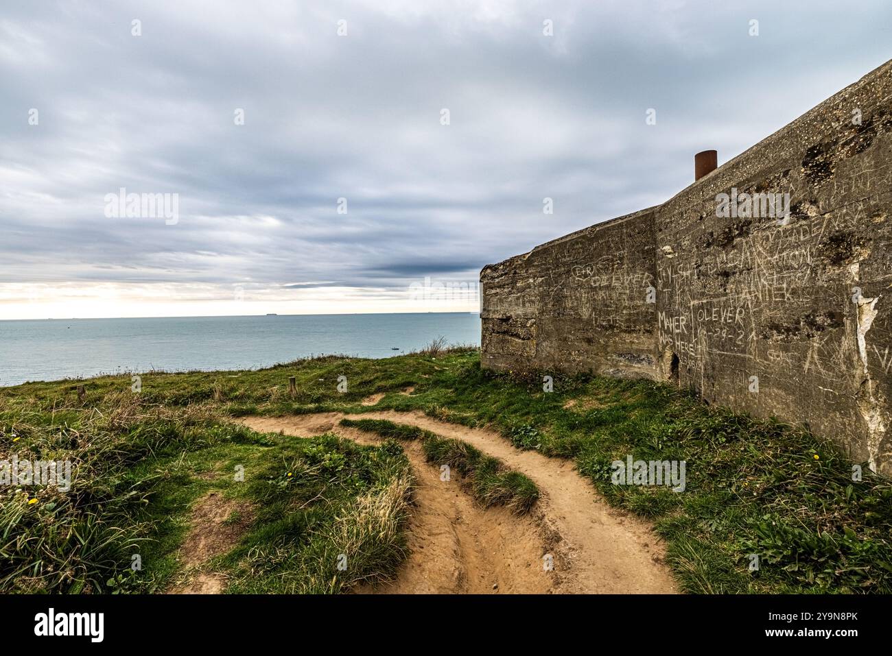 A winding path runs along a coastal cliff with a vintage stone wall ...
