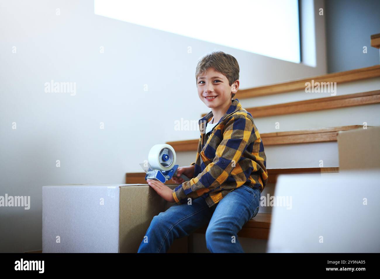 Moving, portrait and child with tape for boxes on stairs for packing ...
