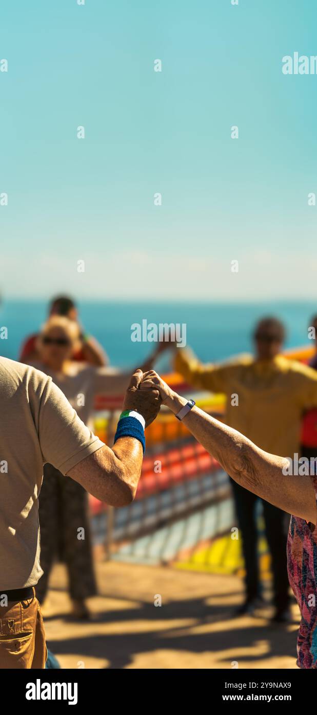 Group of elderly people with their arms raised holding hands dancing ...