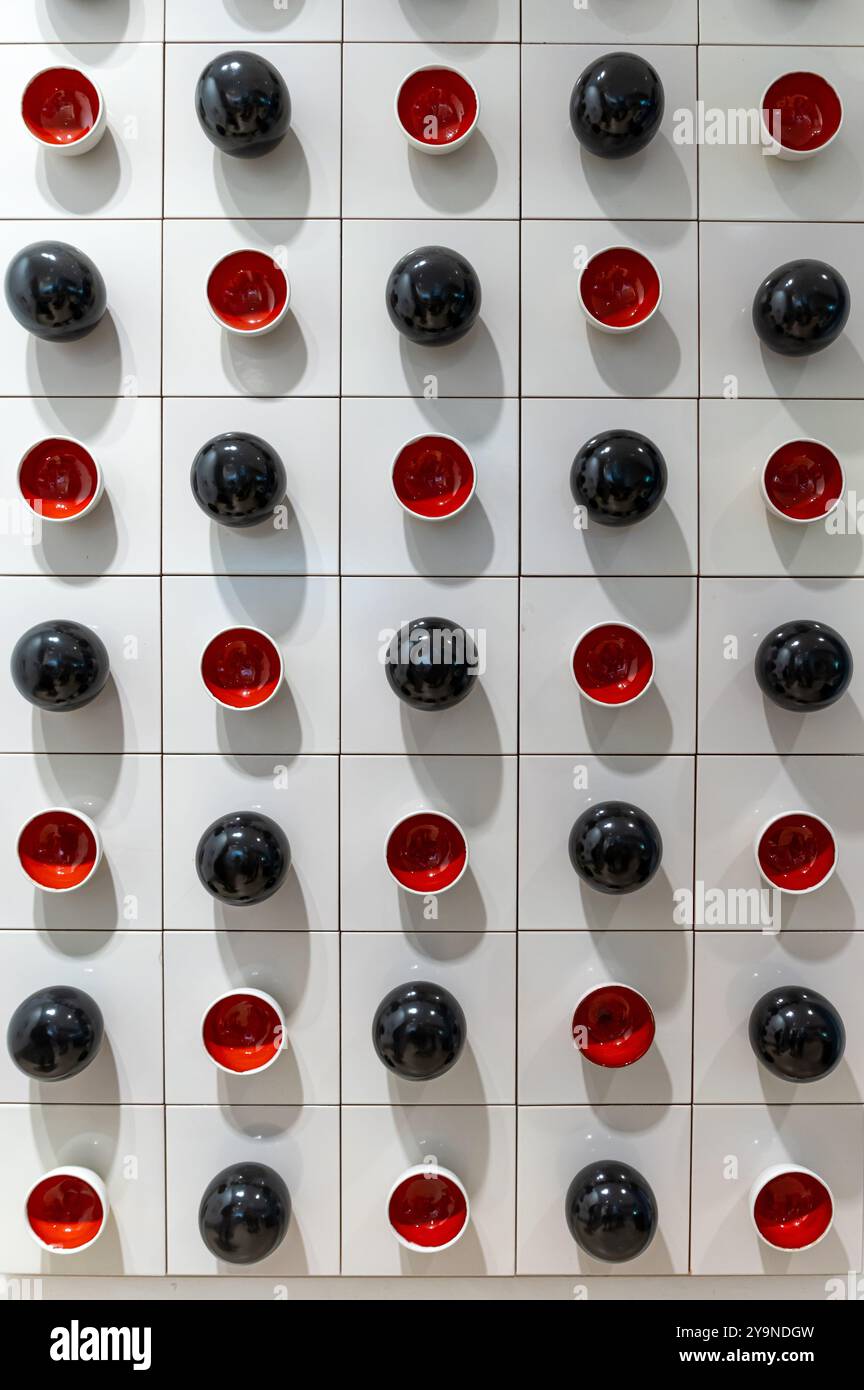 A striking wall displays alternating black and red spherical elements ...