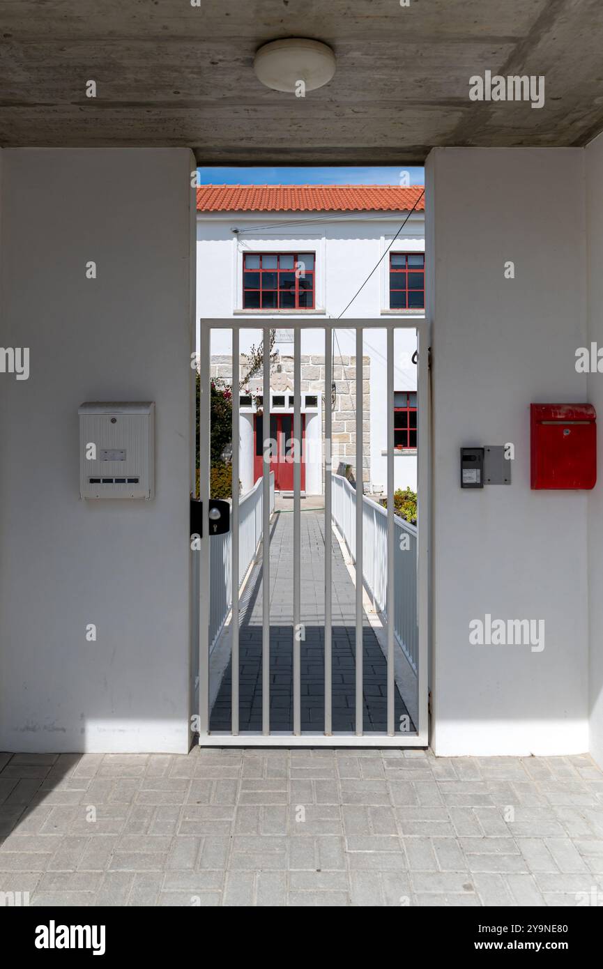 The entrance features a gated pathway leading to a classic building with red doors Stock Photo ...