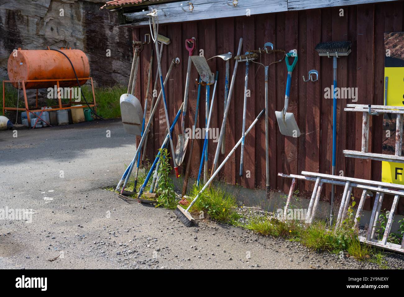 Shovels and rakes hanging on a wall Stock Photo - Alamy