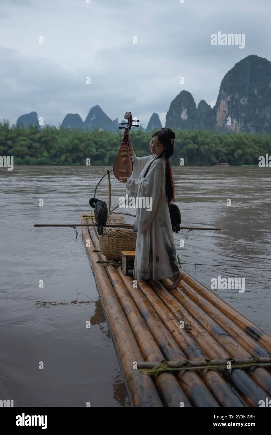 Hanfu girl smiling over Li River puts a pipa traditional instrument in ...