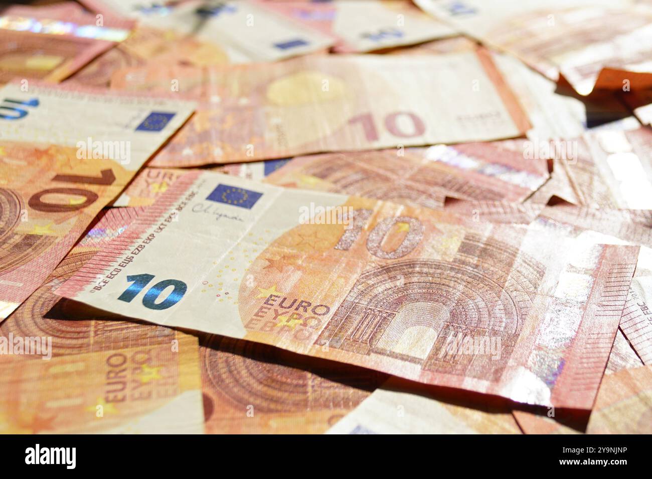Sunlit 10 (ten) euro notes lying on the surface. Paper money prepared ...