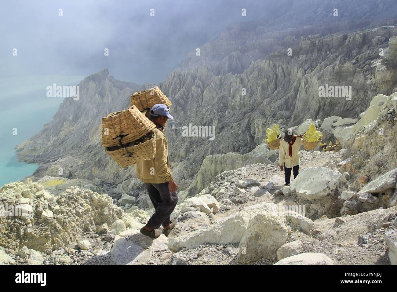Sulfur miners climb the caldera walls of Ijen crater carrying an ...