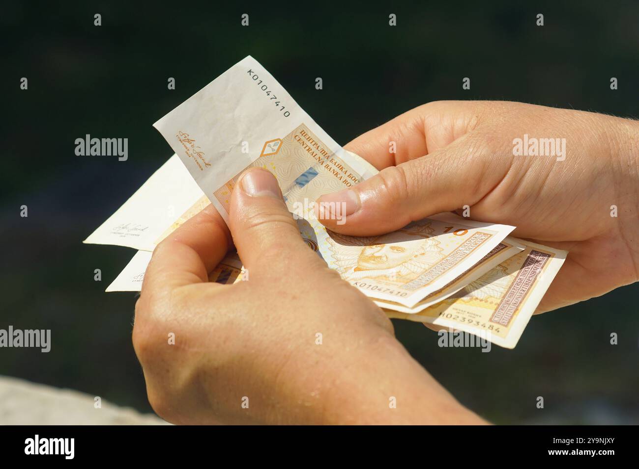 A man counting money: hands sort through 10 and 100 Bosnian convertible ...