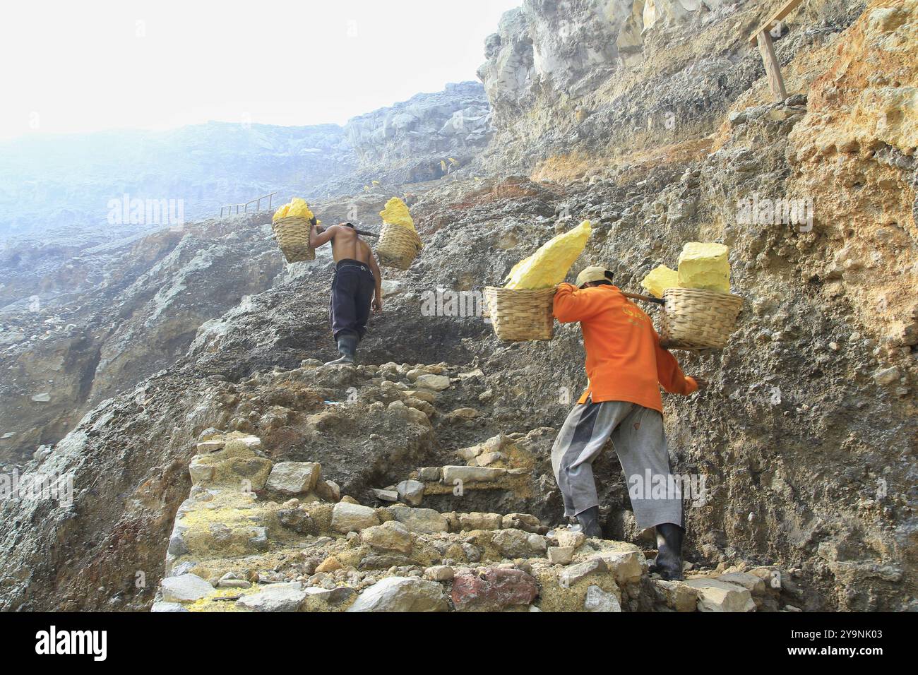 Sulfur miners climb the caldera walls of Ijen crater carrying an ...