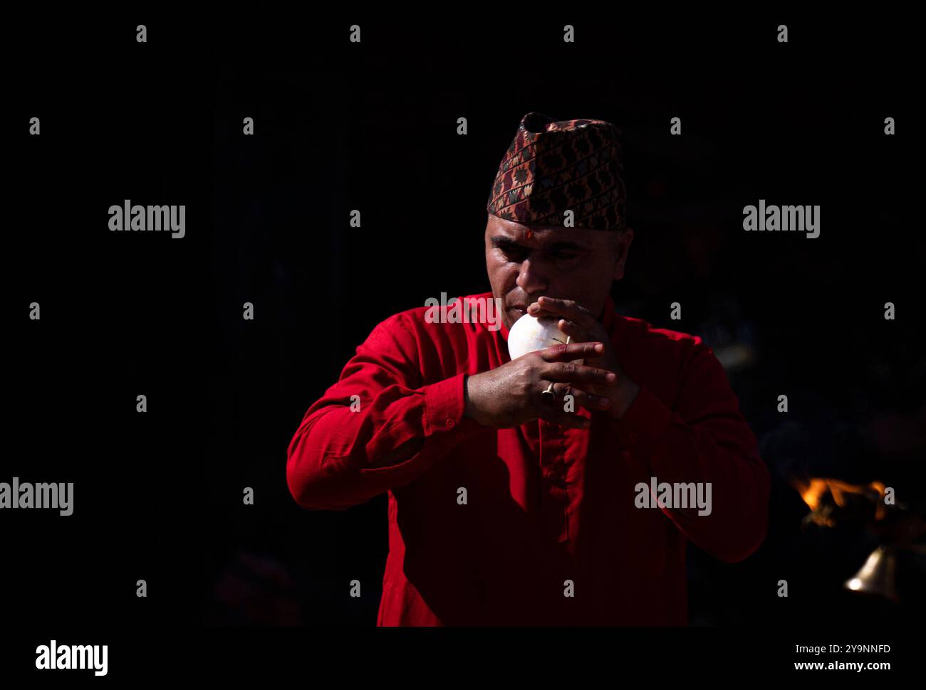 A priest blows the conch while he performs a ritual during Dashain ...