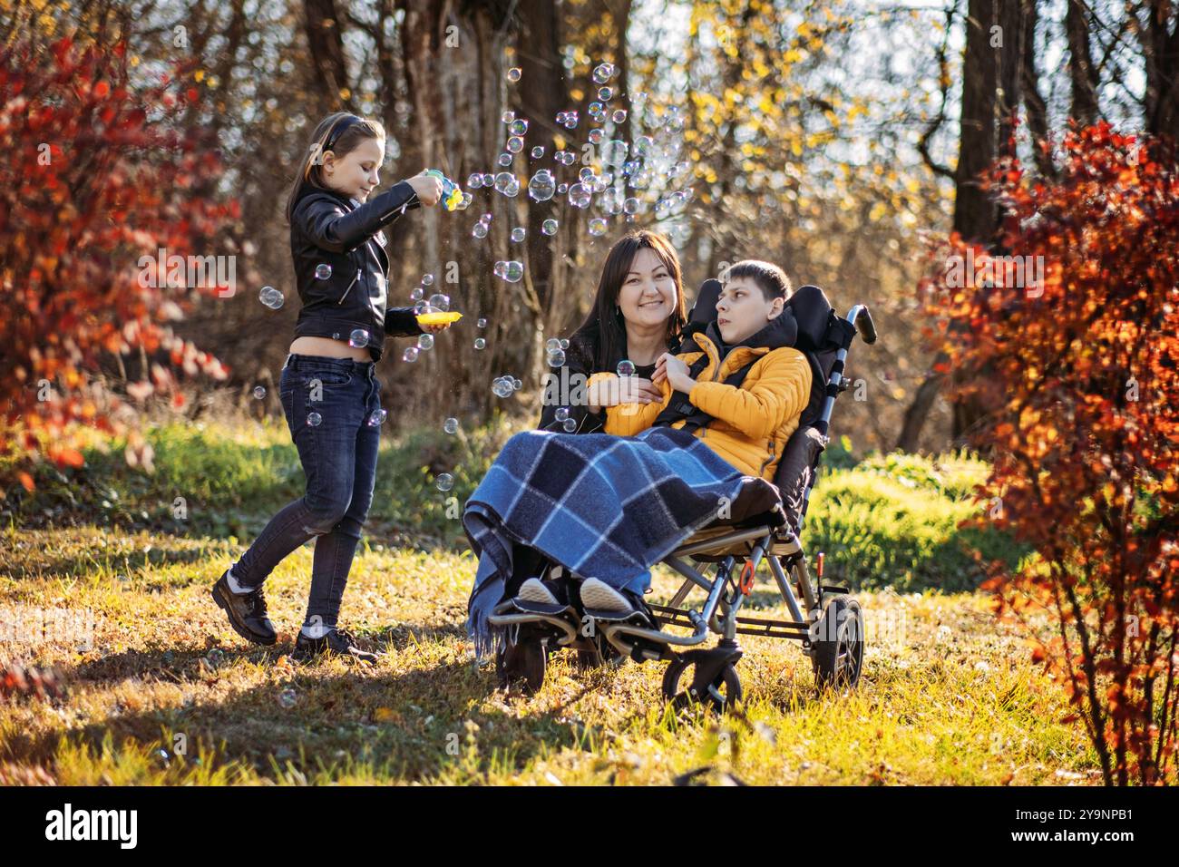 Mother and sibling engaging with child in wheelchair during outdoor ...