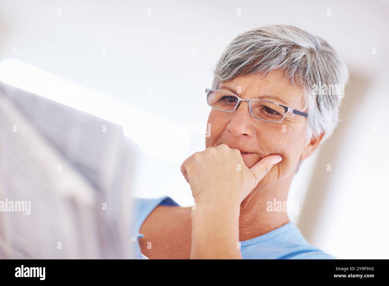 Elderly woman, newspaper and thinking in home, headline announcement ...