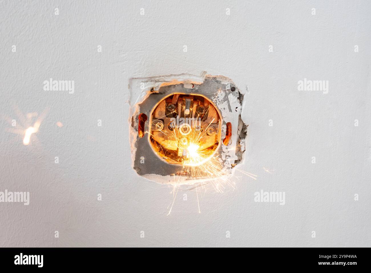 Short circuit sparks and flame in a striped broken outlet on a white ...