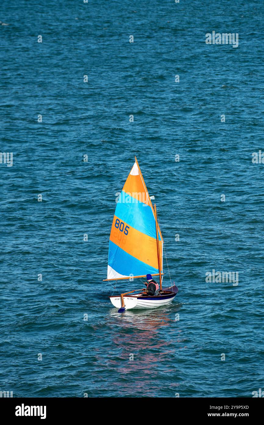 small single-handed sailing dinghy alone on a deep blue sea Stock Photo ...