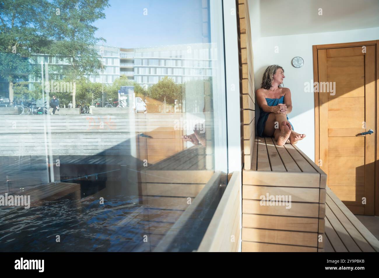 Woman In Sauna Next To Big Window With Urban Scene Stock Photo - Alamy