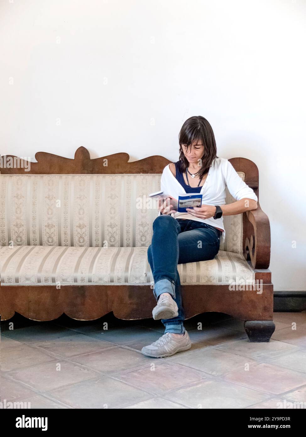 Tourist woman reading guide book while sitting on a vintage bench Stock ...