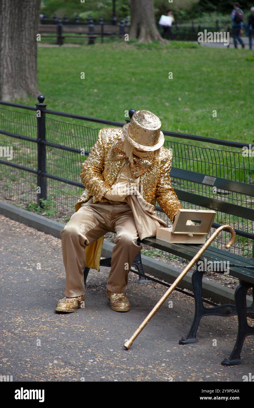 Man in gold sitting on park bench in New York City Stock Photo - Alamy