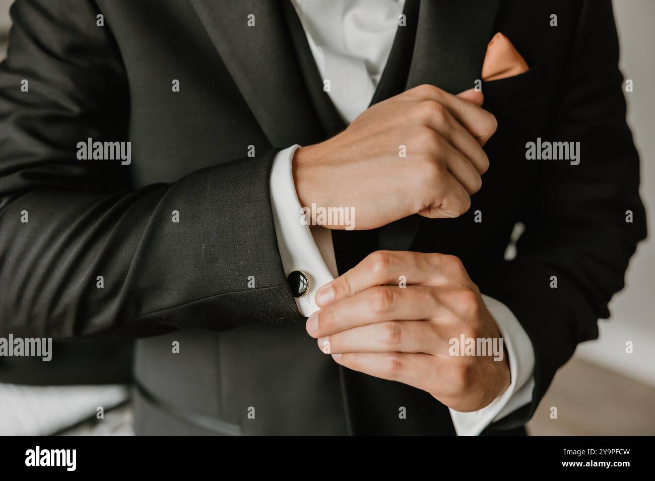 Groom adjusting his cufflinks while wearing a black suit Stock Photo ...