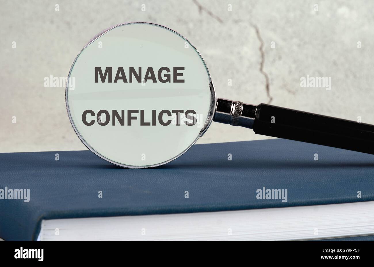 MANAGE CONFLICTS words through a magnifying glass on the wall. Concept ...
