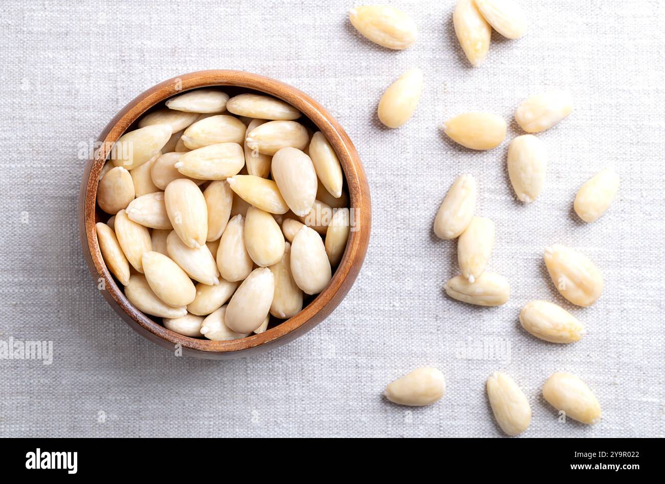 Freshly blanched almonds in wooden bowl on linen. Shelled almonds that ...