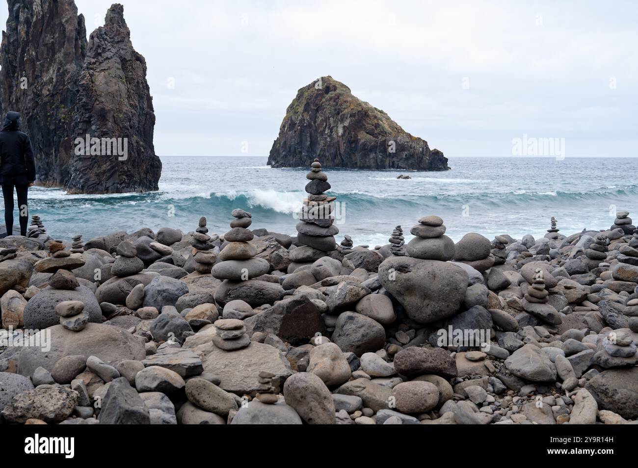 Stacked stones on Ilhéus da Janela beach with towering rock formations ...
